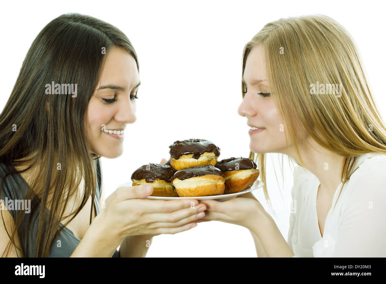 Girls hold cakes on a plate and appetizingly at them look. The isolated ...
