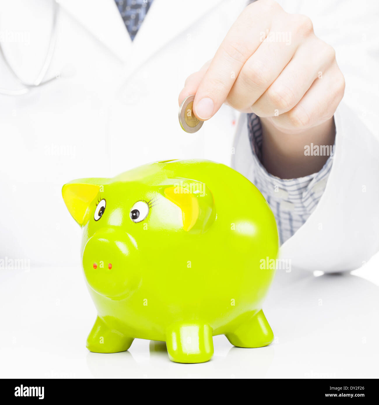 Medical doctor putting a coin into piggy bank as an idea for healthcare ...