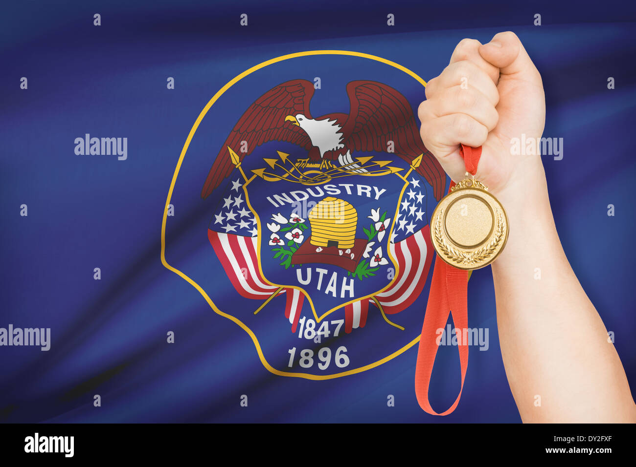 Sportsman holding gold medal with State of Utah flag on background ...