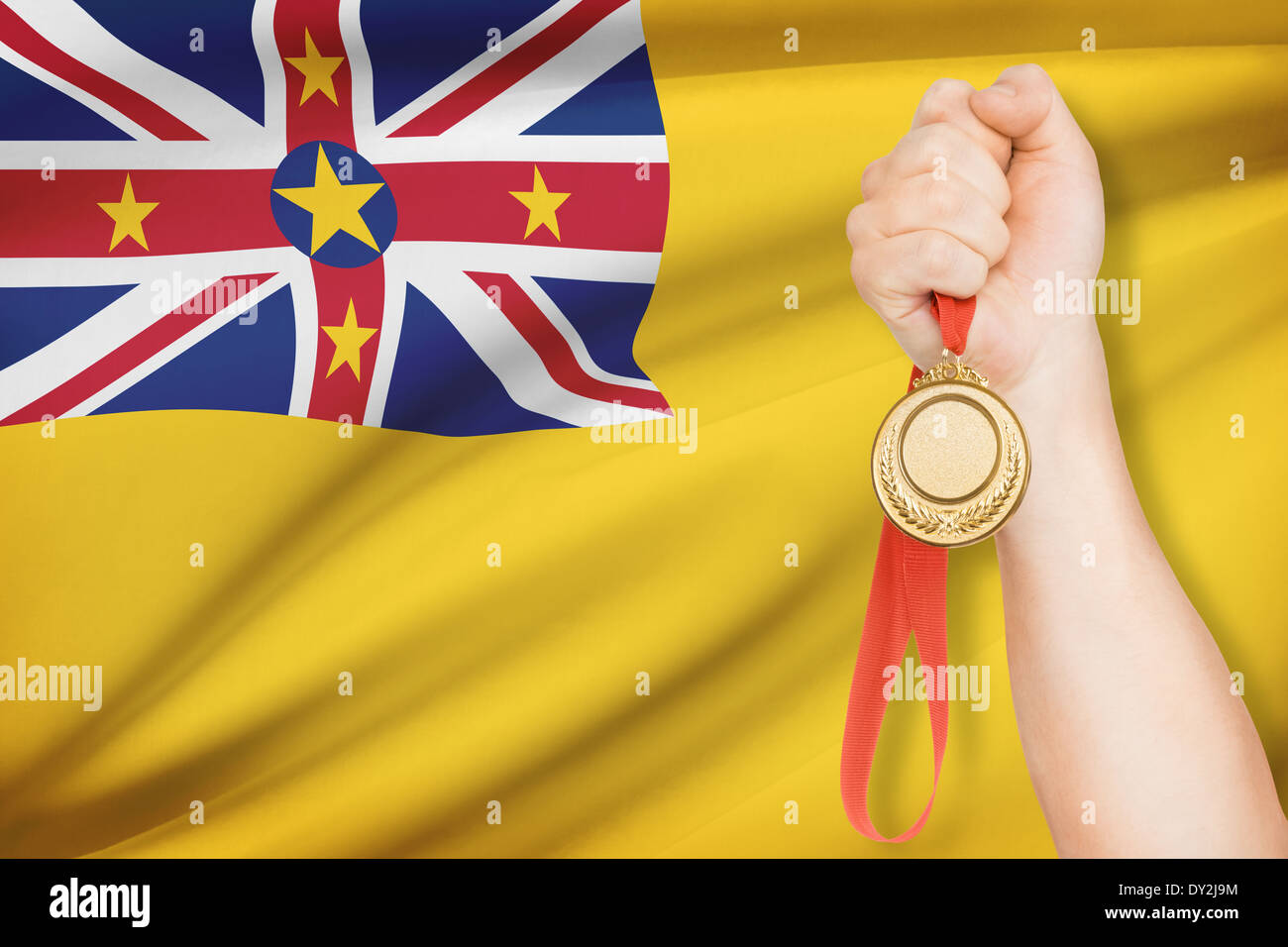 Sportsman holding gold medal with flag on background - Niue Stock Photo ...