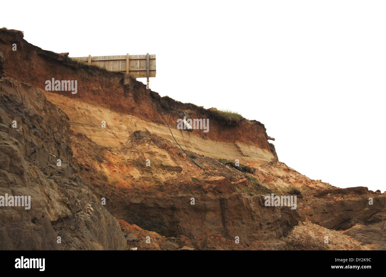Eroding cliffs with overhanging garden fence at Happisburgh, Norfolk ...