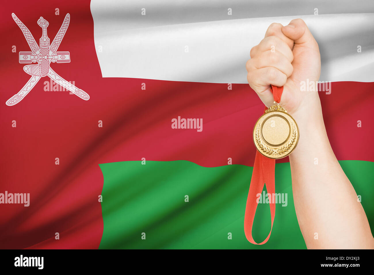 Sportsman holding gold medal with flag on background - Sultanate of ...