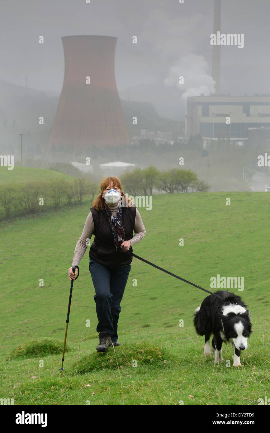 Woman wearing smog mask while walking dogs near Ironbridge Power ...