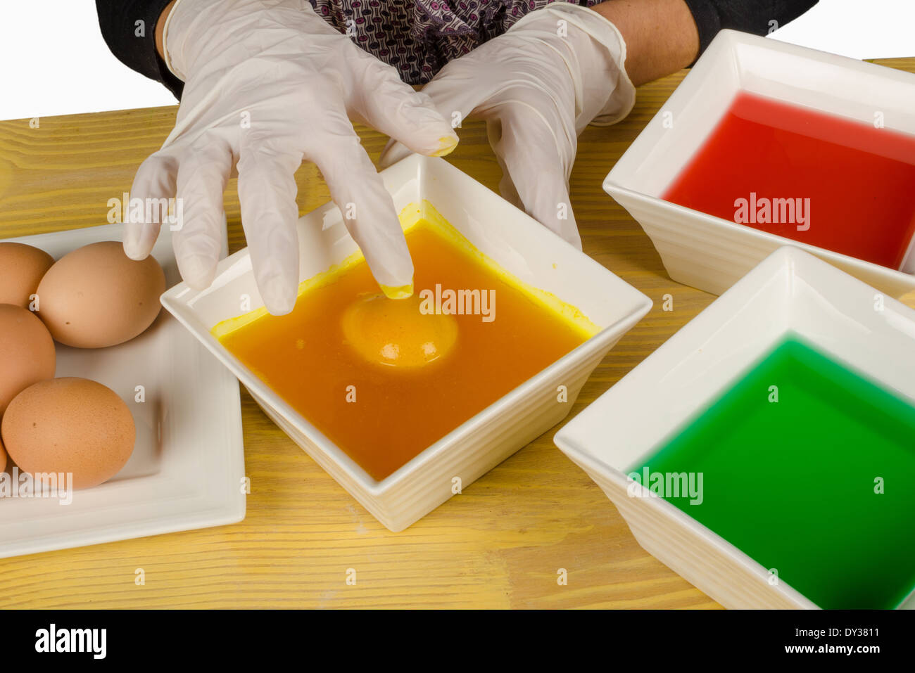 Hands coloring Easter eggs by dipping them in bowls with dye Stock ...
