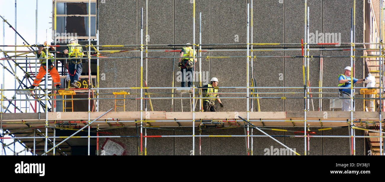 Workmen erecting scaffolding around obsolete social housing block prior ...