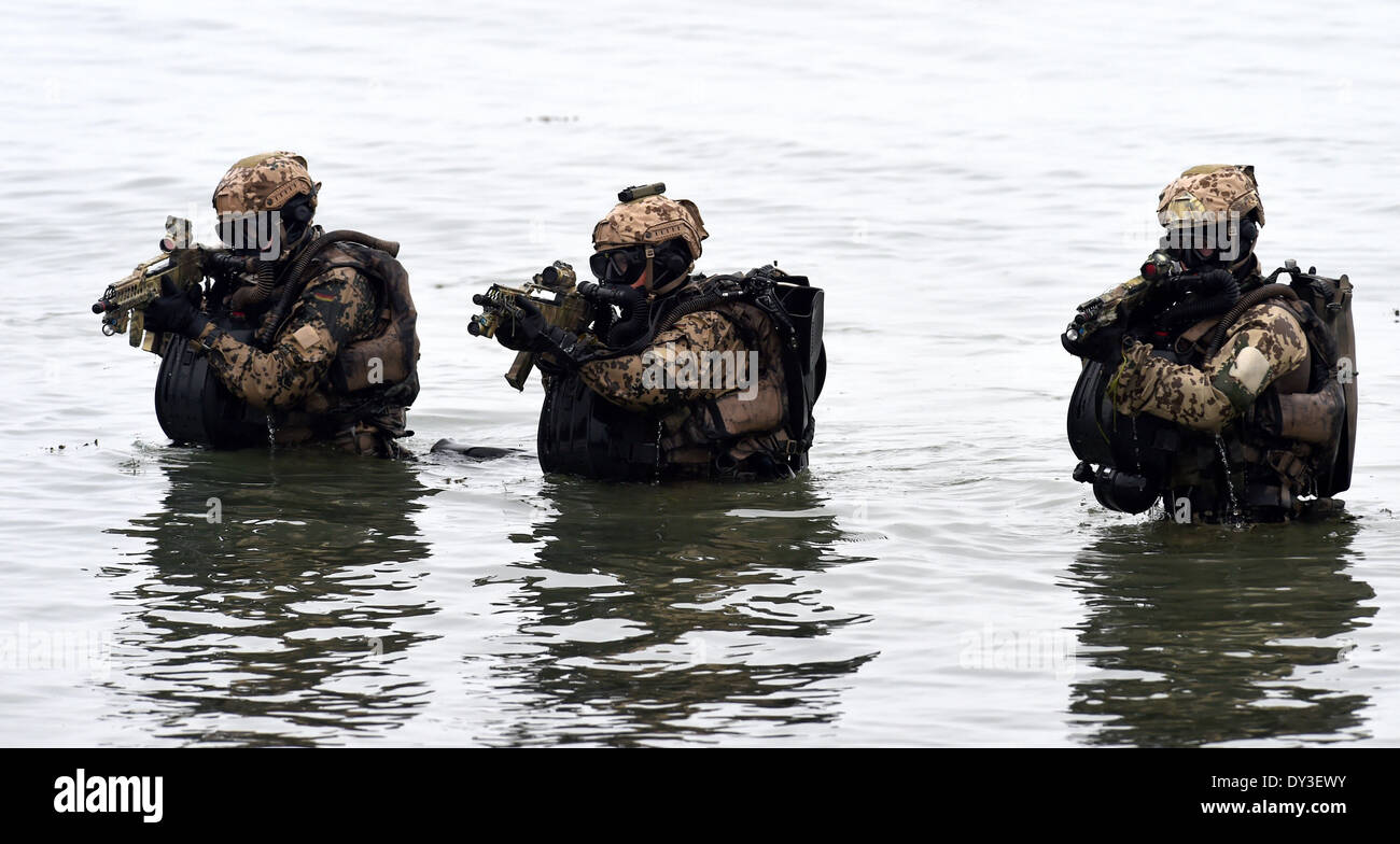 Three German Navy frogmen wade through the water as they arrive on the ...