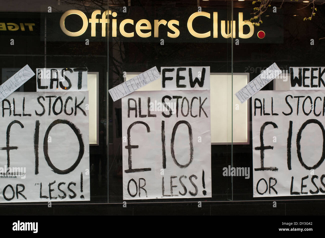 Sale signs in an Officers Club shop front with people walking past ...
