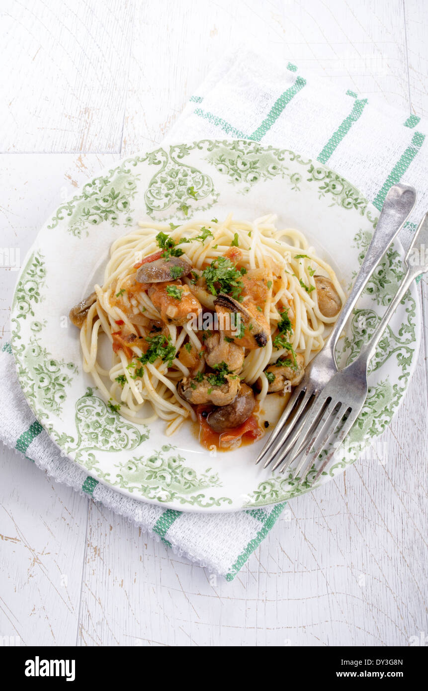 Italian dish with spaghetti, mussels, tomato, olive, chili and parsley ...