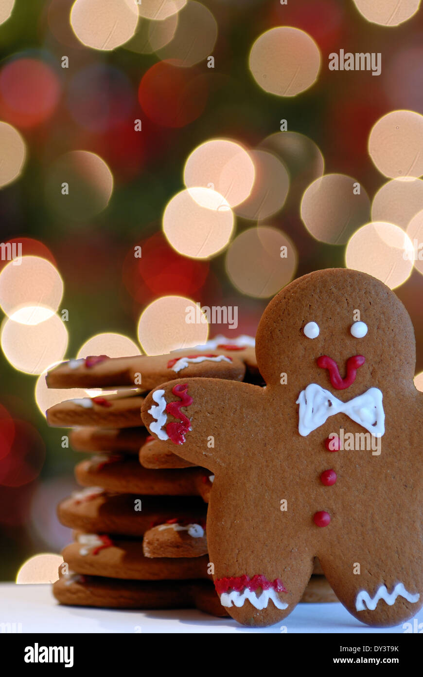 A smiling gingerbread man and a stack of more cookies in front of ...