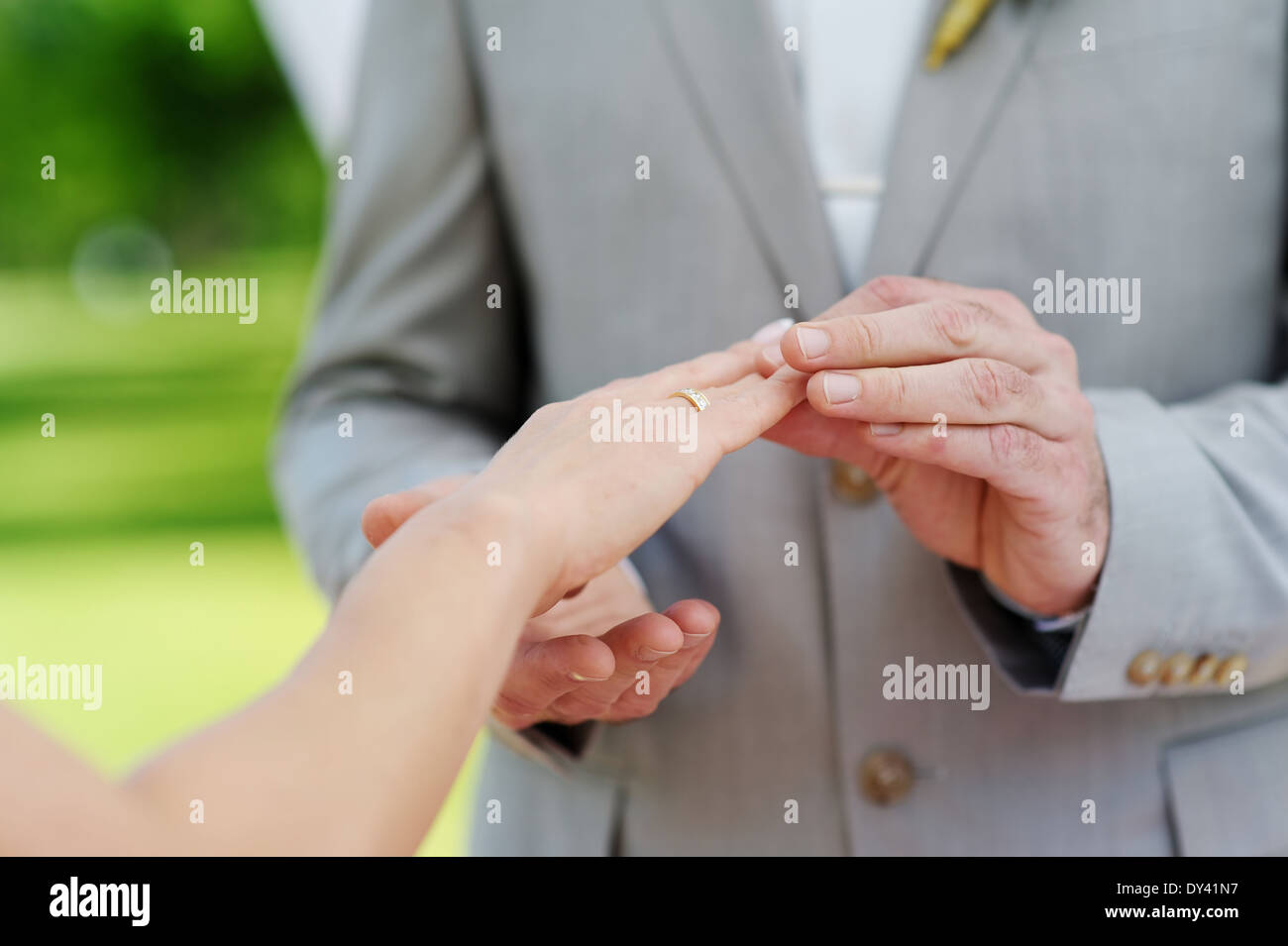 Groom putting a wedding ring on bride's finger Stock Photo - Alamy