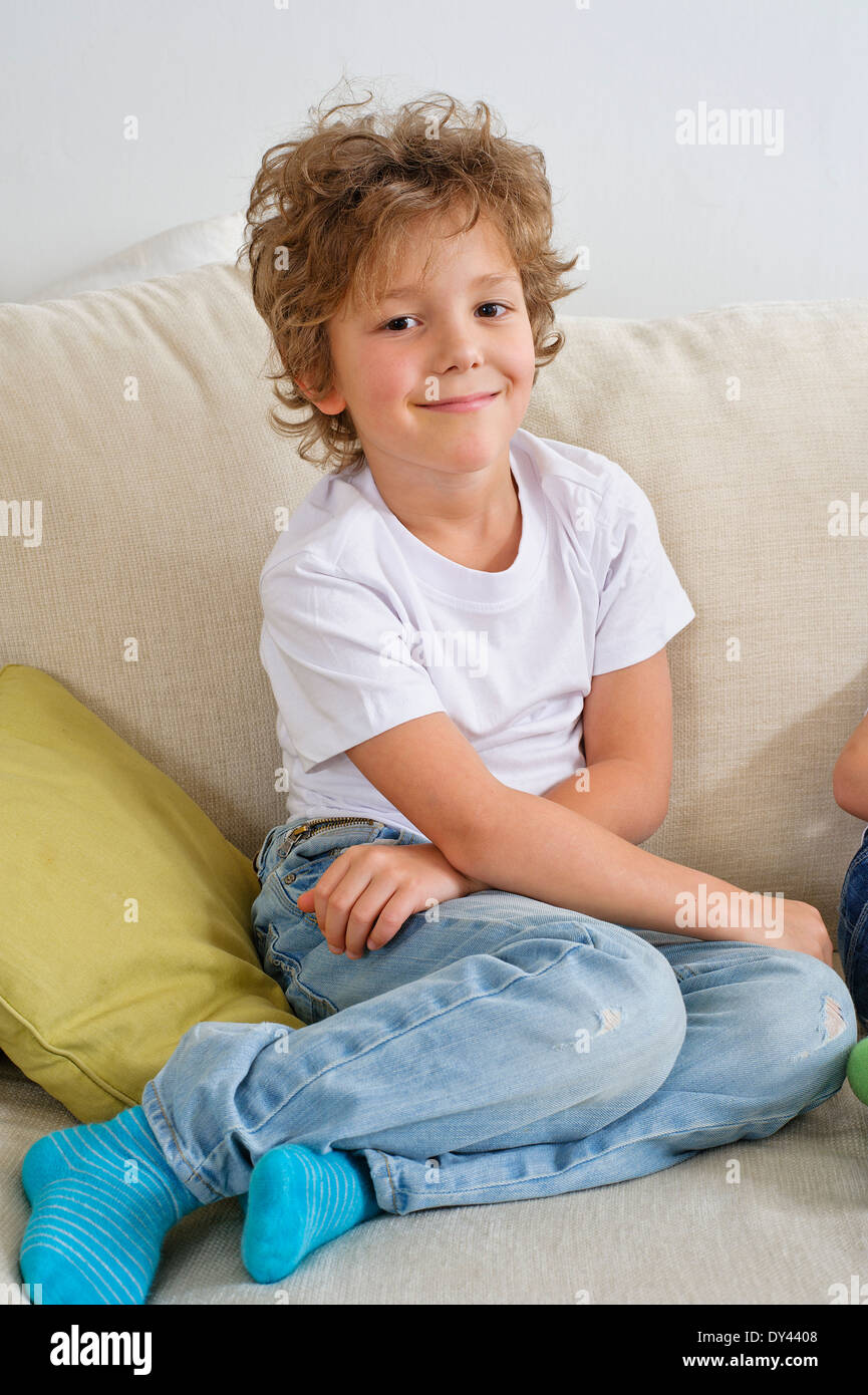 Young boy sitting on sofa looking at camera Stock Photo - Alamy