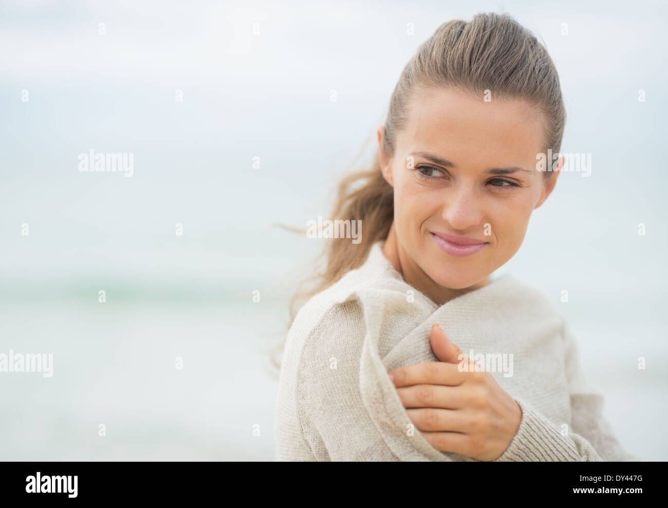 Happy young woman on cold beach looking on copy space Stock Photo - Alamy