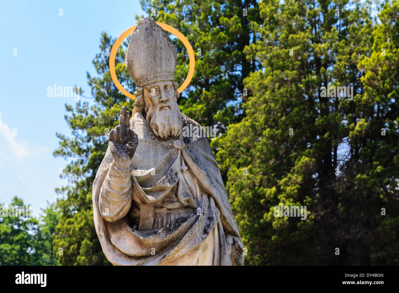 A stone statue of a saint outdoor with a bishop's hat and typical hand ...