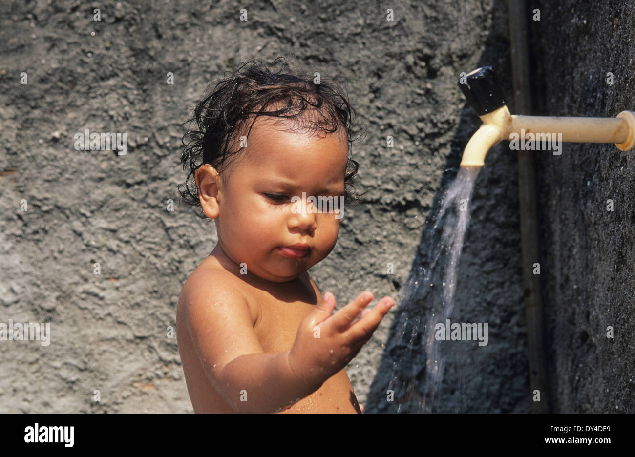 Young child with water and water tap, Rocinha Favela, Rio de Janeirio ...