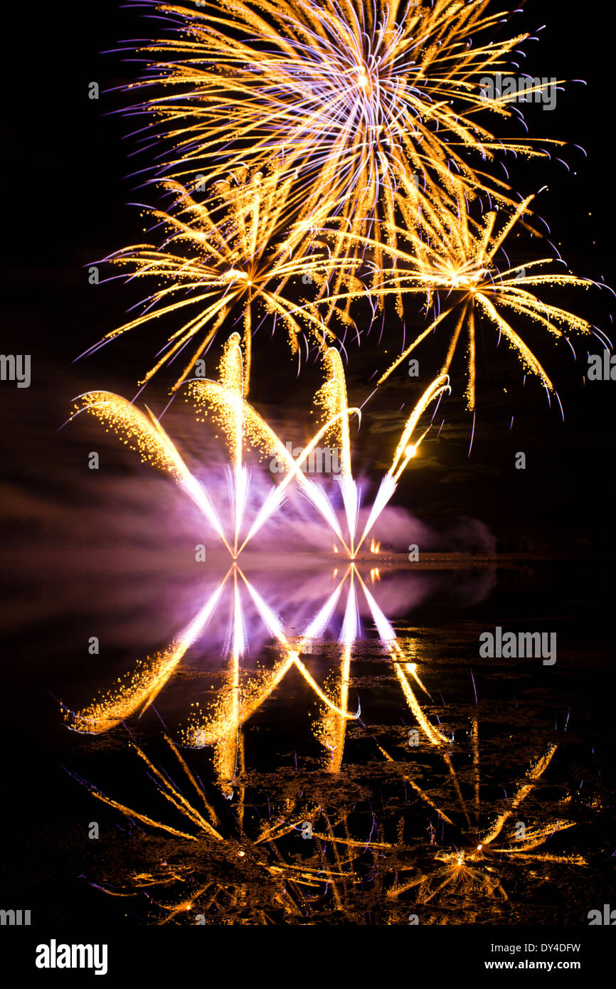 Golden and Purple Fireworks reflected in a murky lake Stock Photo - Alamy
