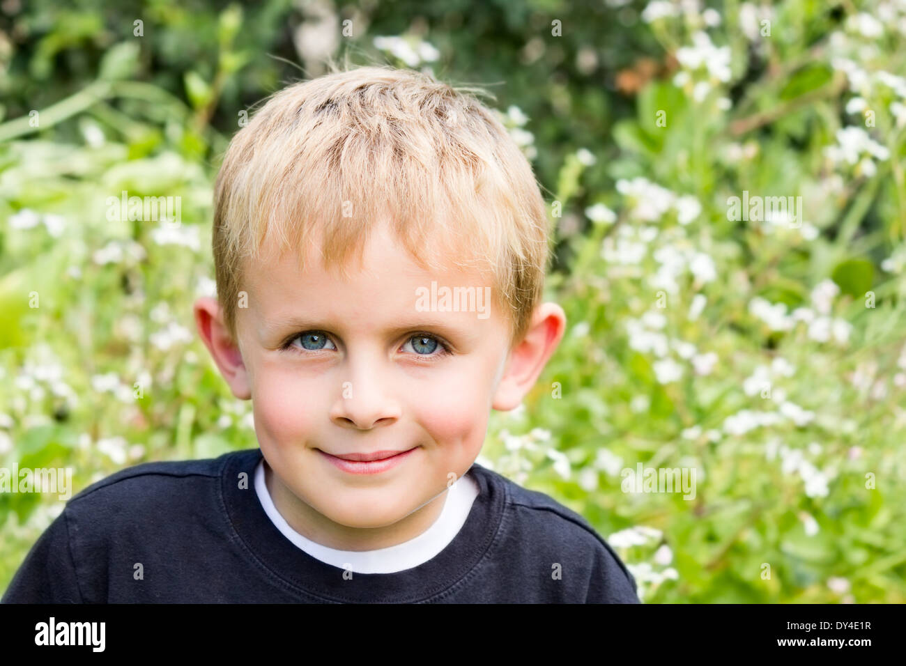 Young Boy Sitting in the Garden with a shy smile Stock Photo - Alamy