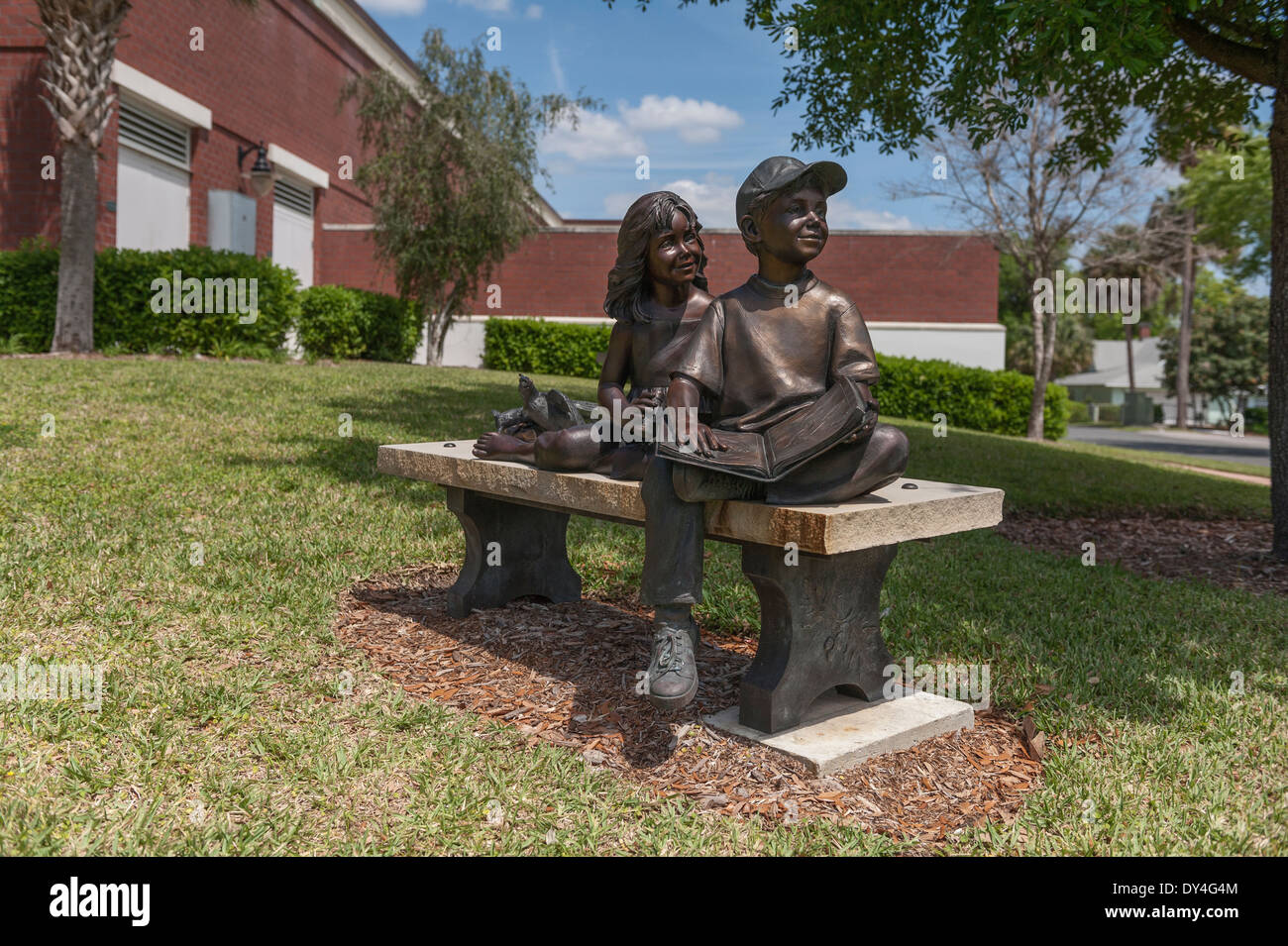 Bronze statue of children reading a book on a bench outside the ...