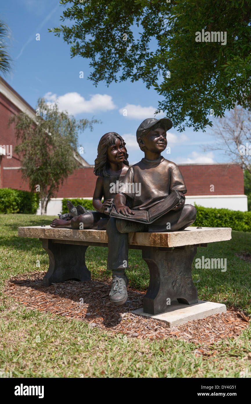 Bronze statue of children reading a book on a bench outside the ...