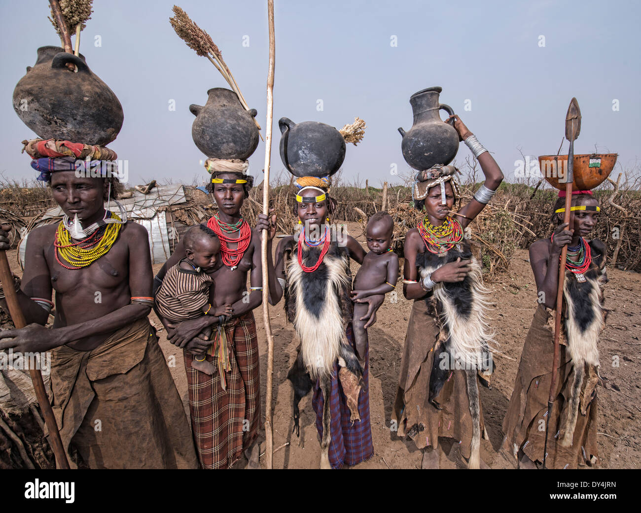 Dassanech women with hyena pelt skins and jugs on their heads in the ...