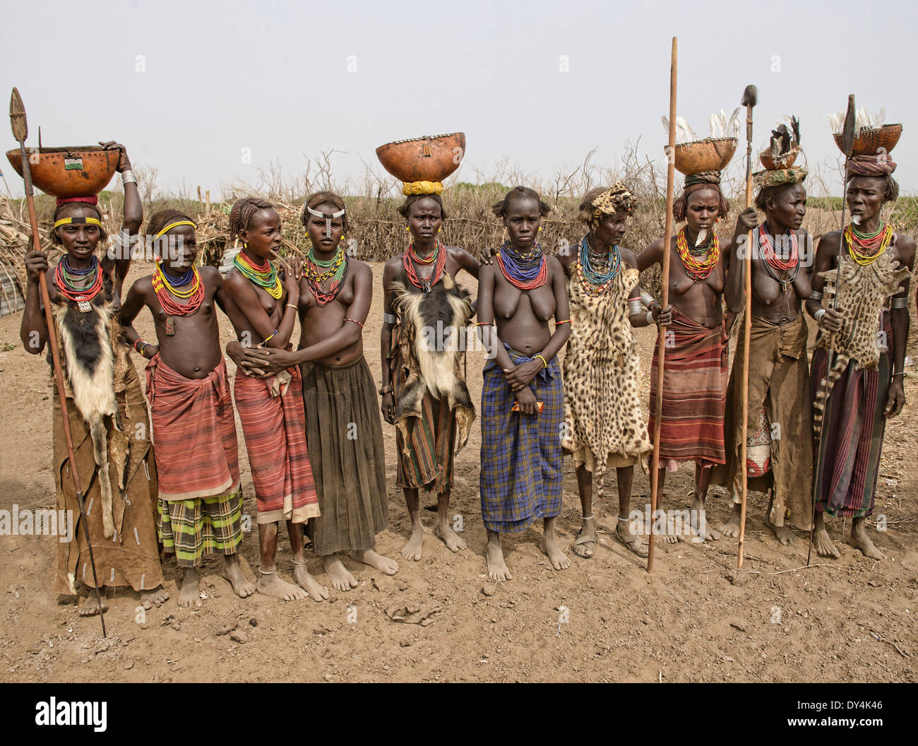 Dassanech women with hyena pelt skins and jugs on their heads in the ...
