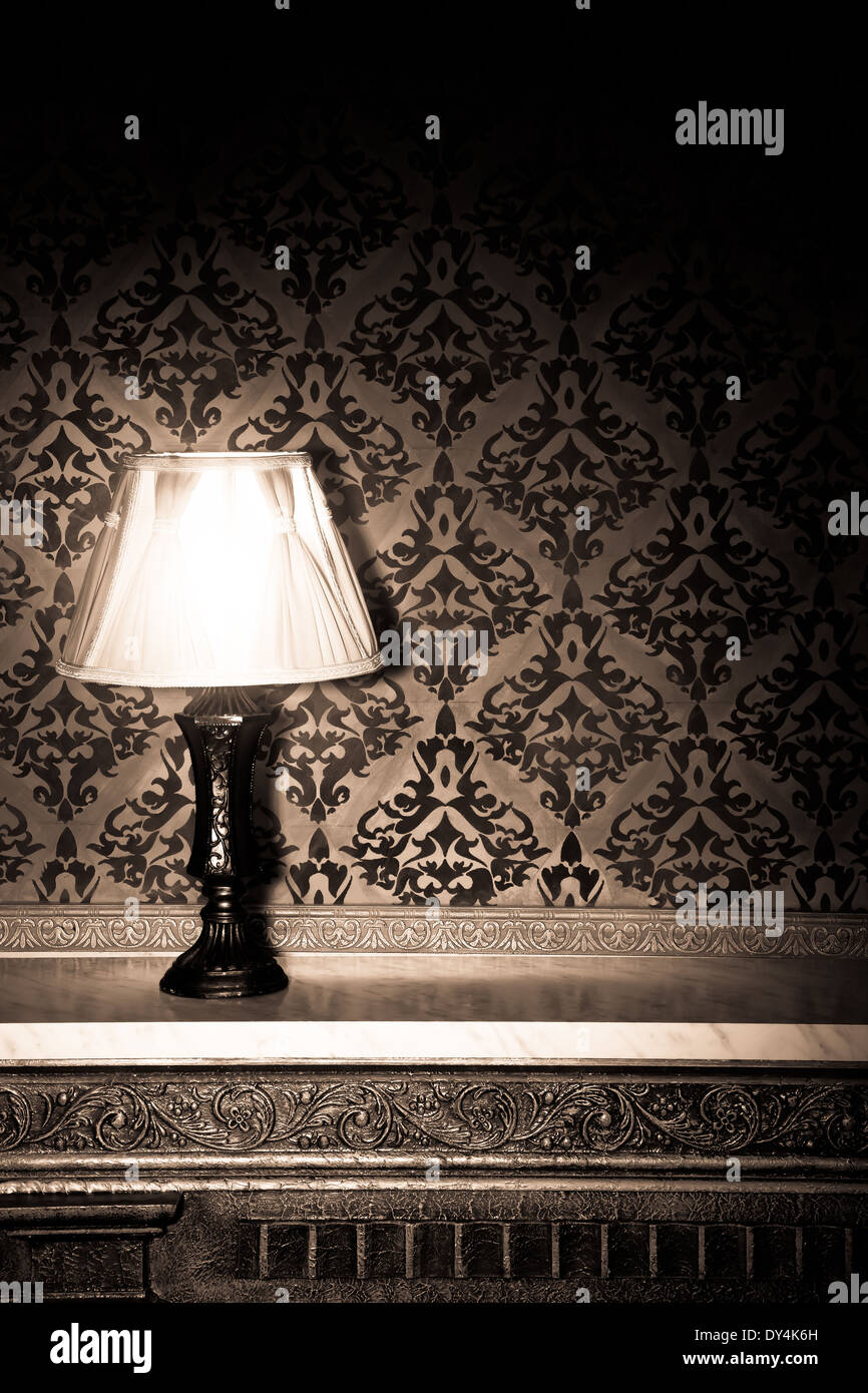 Vintage lamp on old fireplace in room with red rocco pattern. Luxury ...