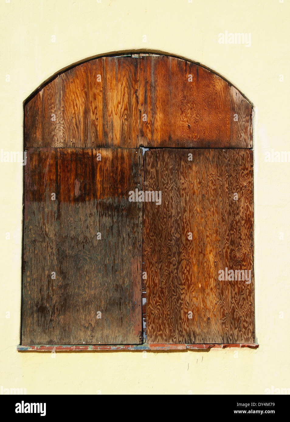 weathered boards over a window on an abandon building, with arch on top ...