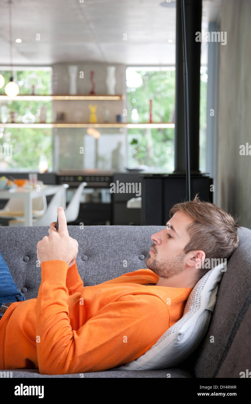 Man lying on sofa using hi-res stock photography and images - Alamy
