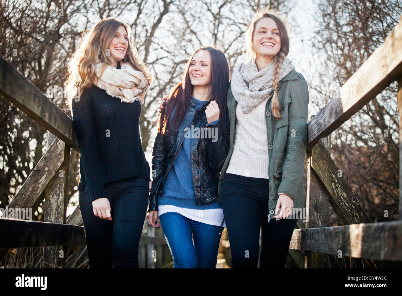 Three female friends strolling over footbridge Stock Photo - Alamy