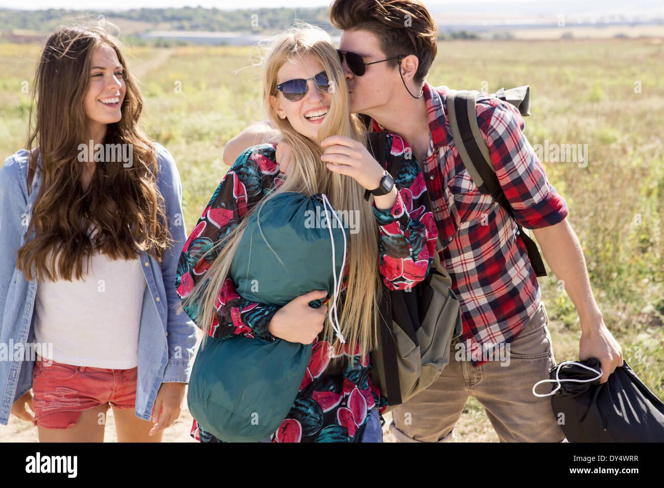 Three friends out hiking, man kissing woman Stock Photo - Alamy