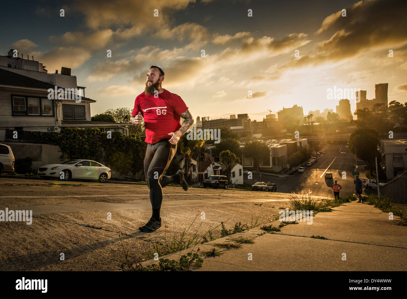 Mid adult male runner and team mates running up a steep city hill Stock ...