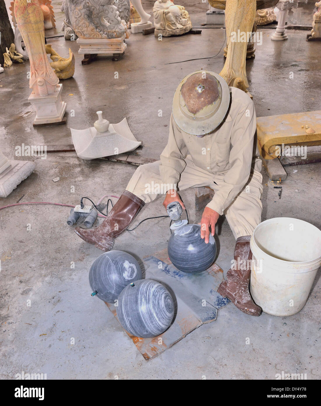 Stone cutter shaping rock with grinder and carving into small ornaments ...