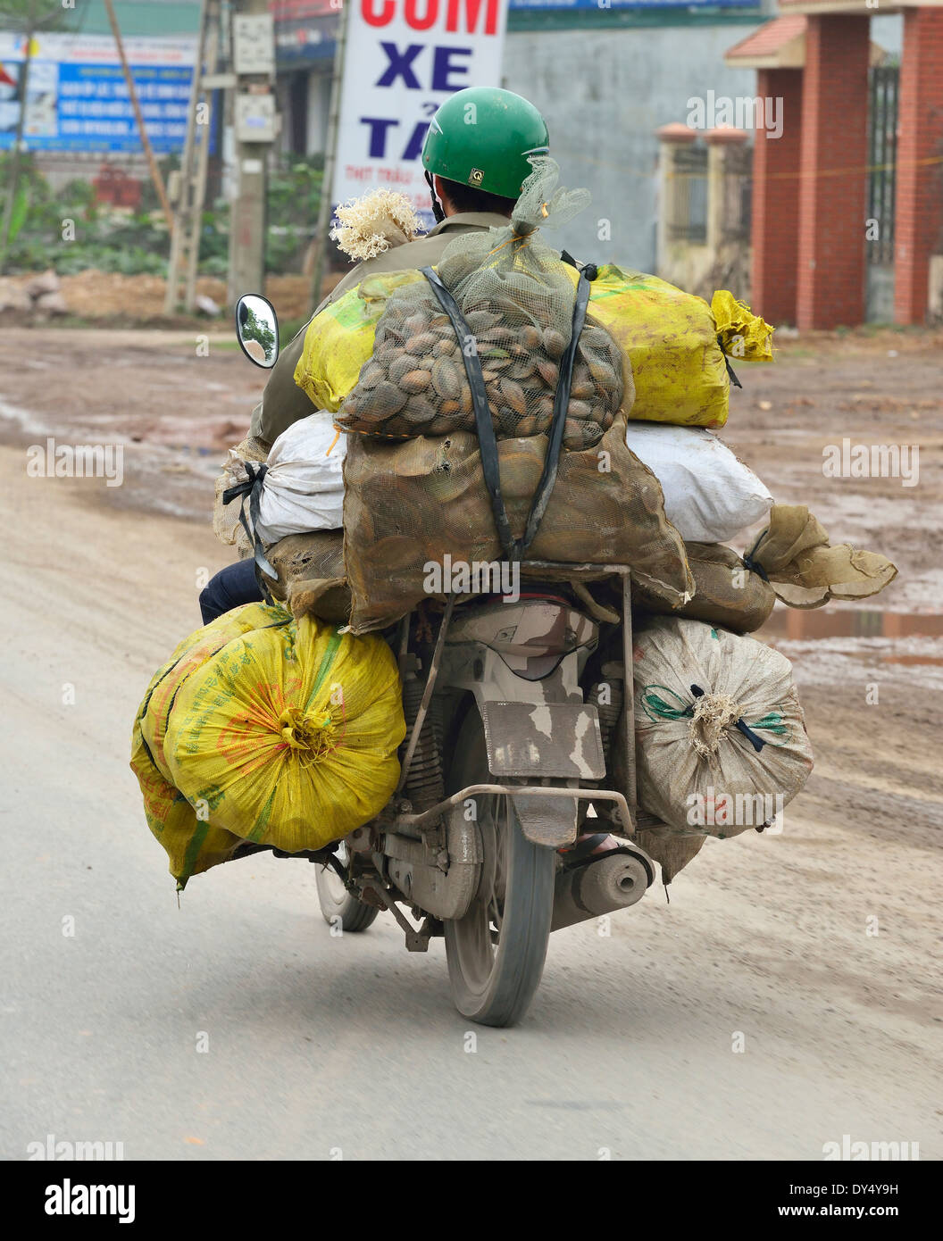 Vietnamese man on a small motorcycle over loaded (by european standards ...