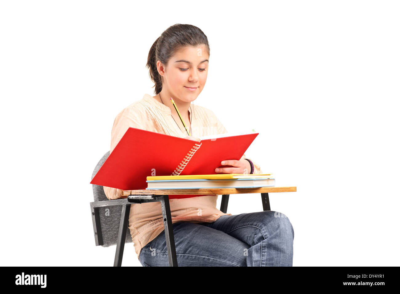 Girl writing in a notebook on a school desk Stock Photo - Alamy