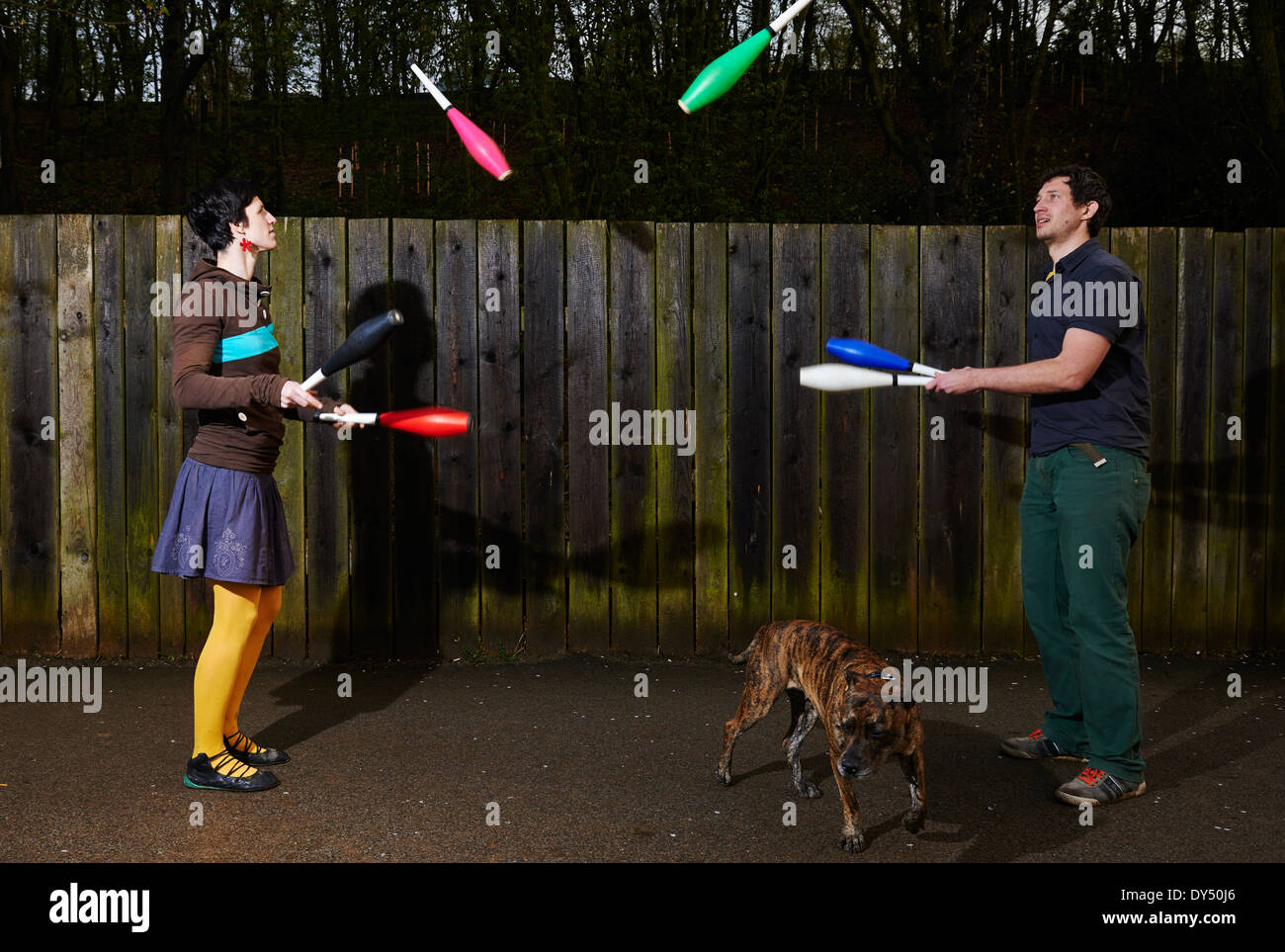 Two people man and woman couple juggling with clubs standing against ...