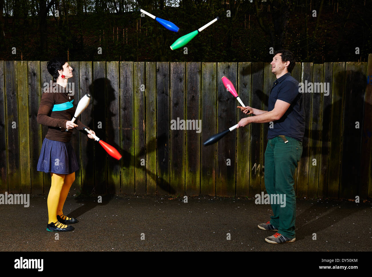 Two people man and woman couple juggling with clubs standing against ...