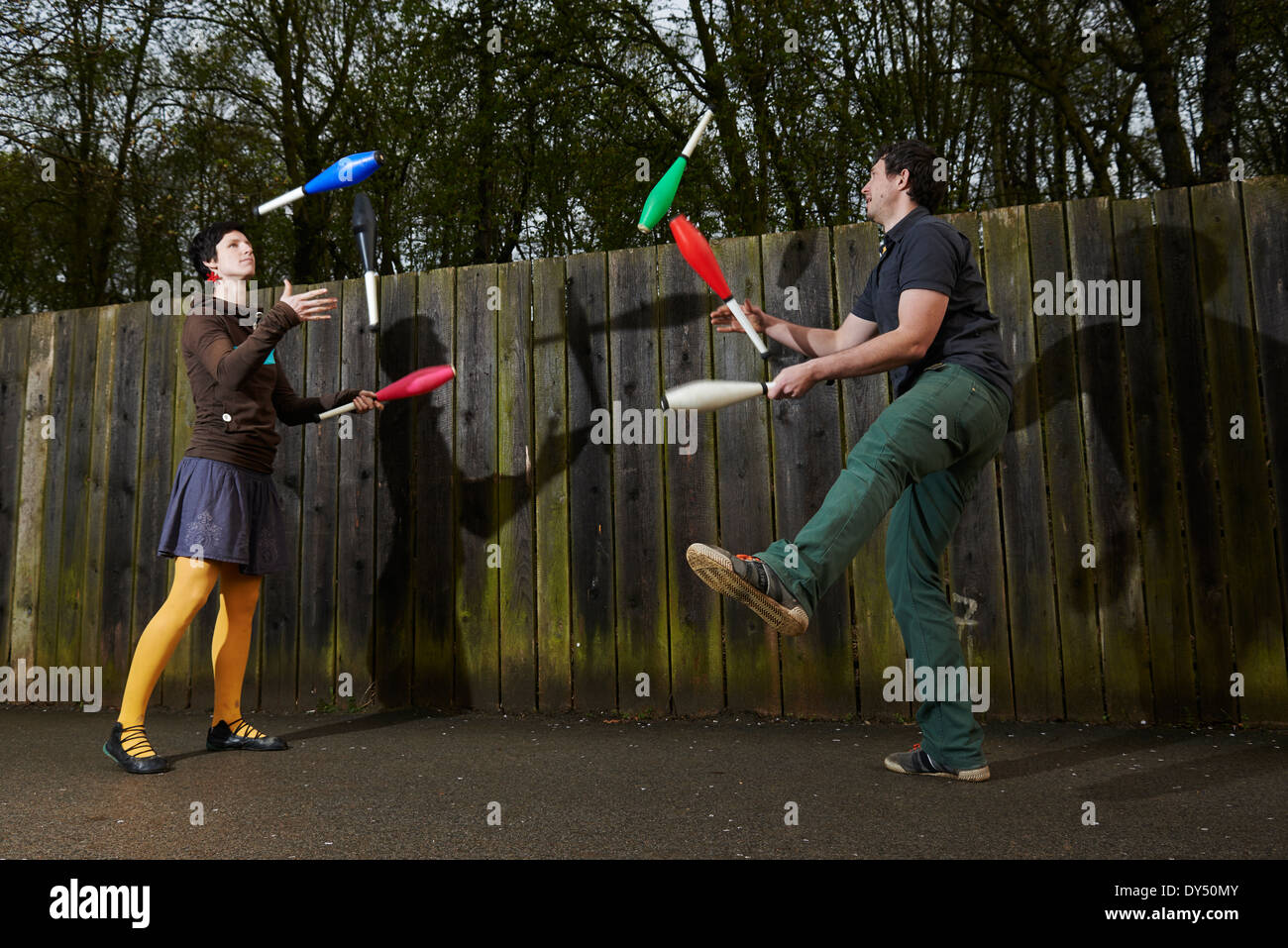 Two people man and woman couple juggling with clubs standing against ...