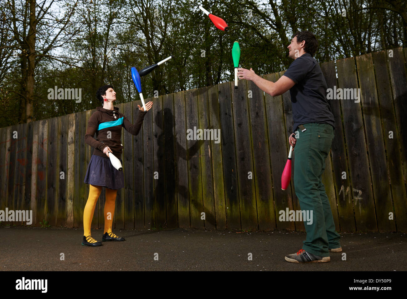 Two people man and woman couple juggling with clubs standing against ...