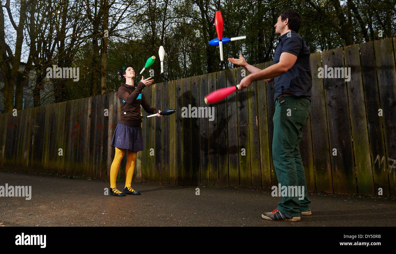 Two people man and woman couple juggling with clubs standing against ...