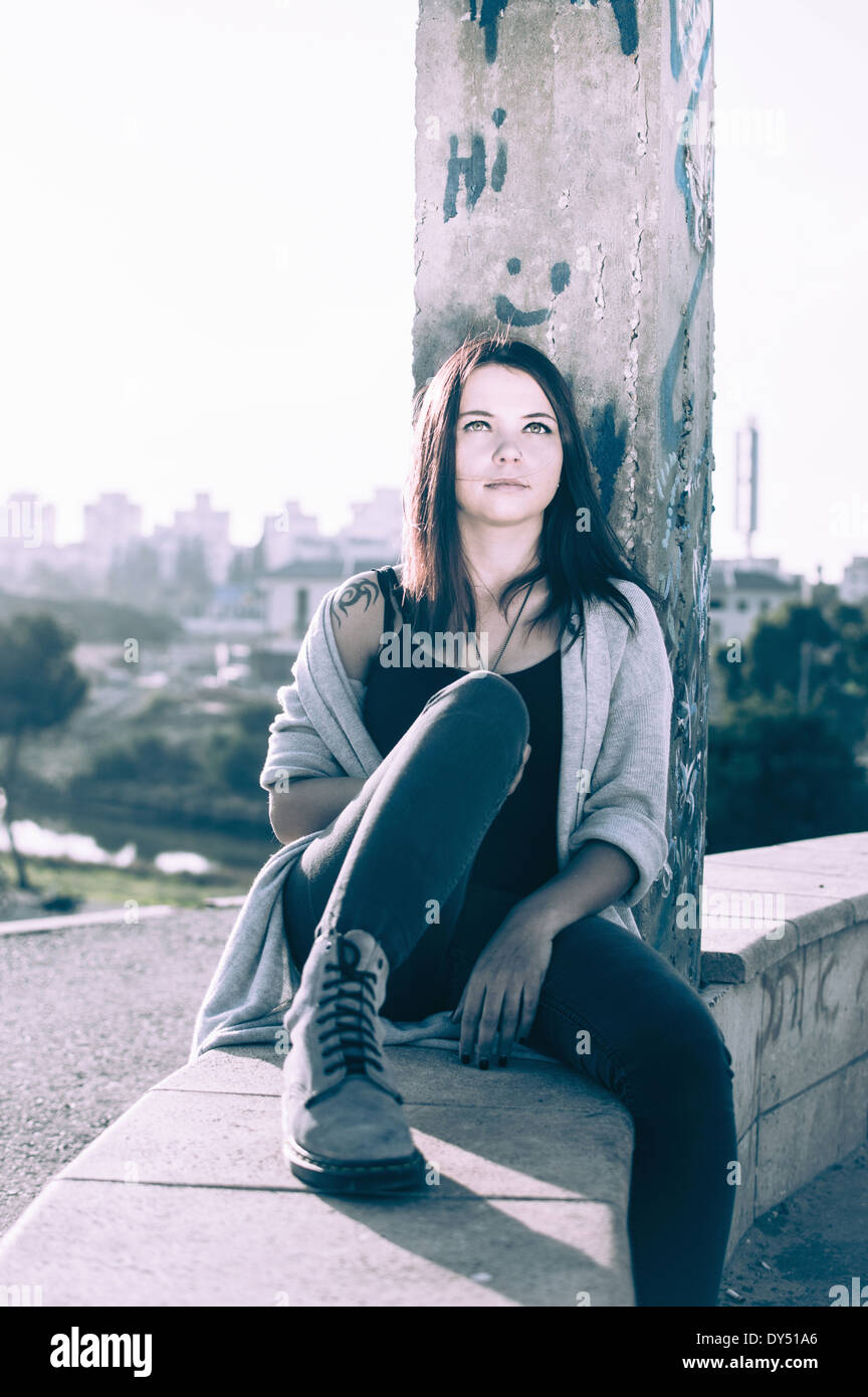 Young woman sitting on wall Stock Photo - Alamy