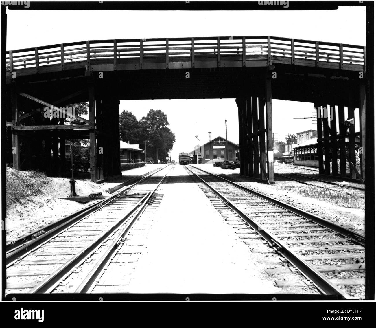 A photograph of an overpass bridge positioned above railroad tracks ...
