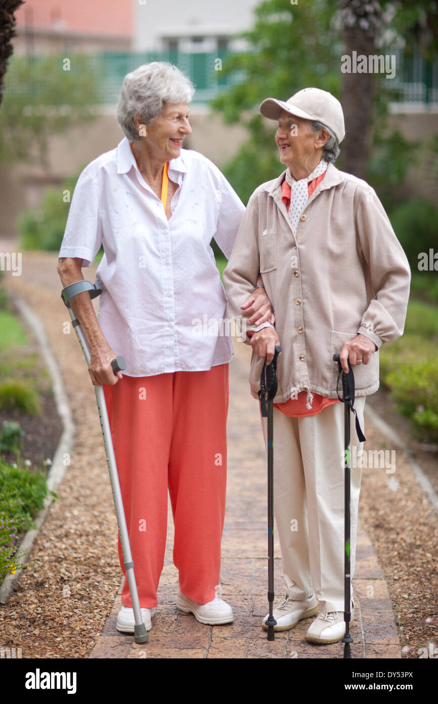Two senior women strolling in retirement villa garden Stock Photo - Alamy