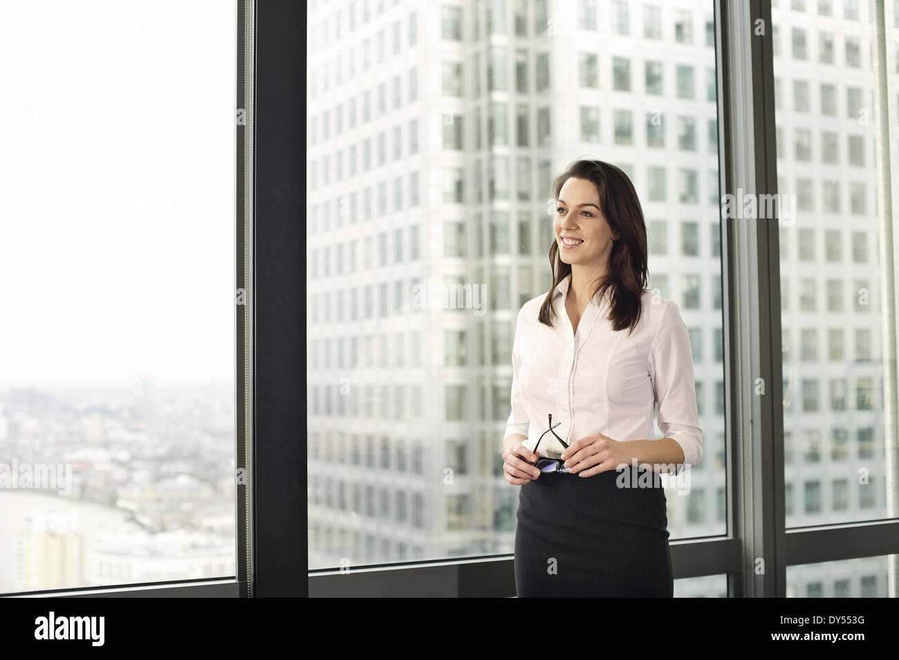Portrait of young businesswoman looking out of office window Stock ...