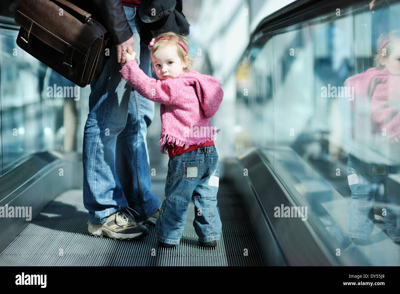 Adorable toddler girl and her father standing on moving escalator Stock ...