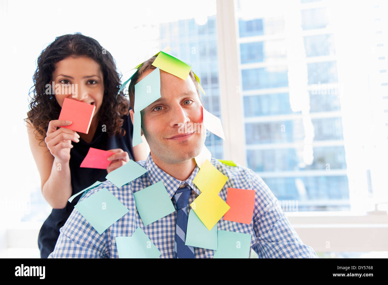 Female office worker covering male colleague with sticky notes Stock ...