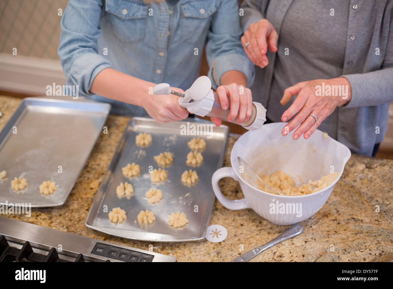 Senior woman and granddaughter piping biscuits onto baking tray Stock ...