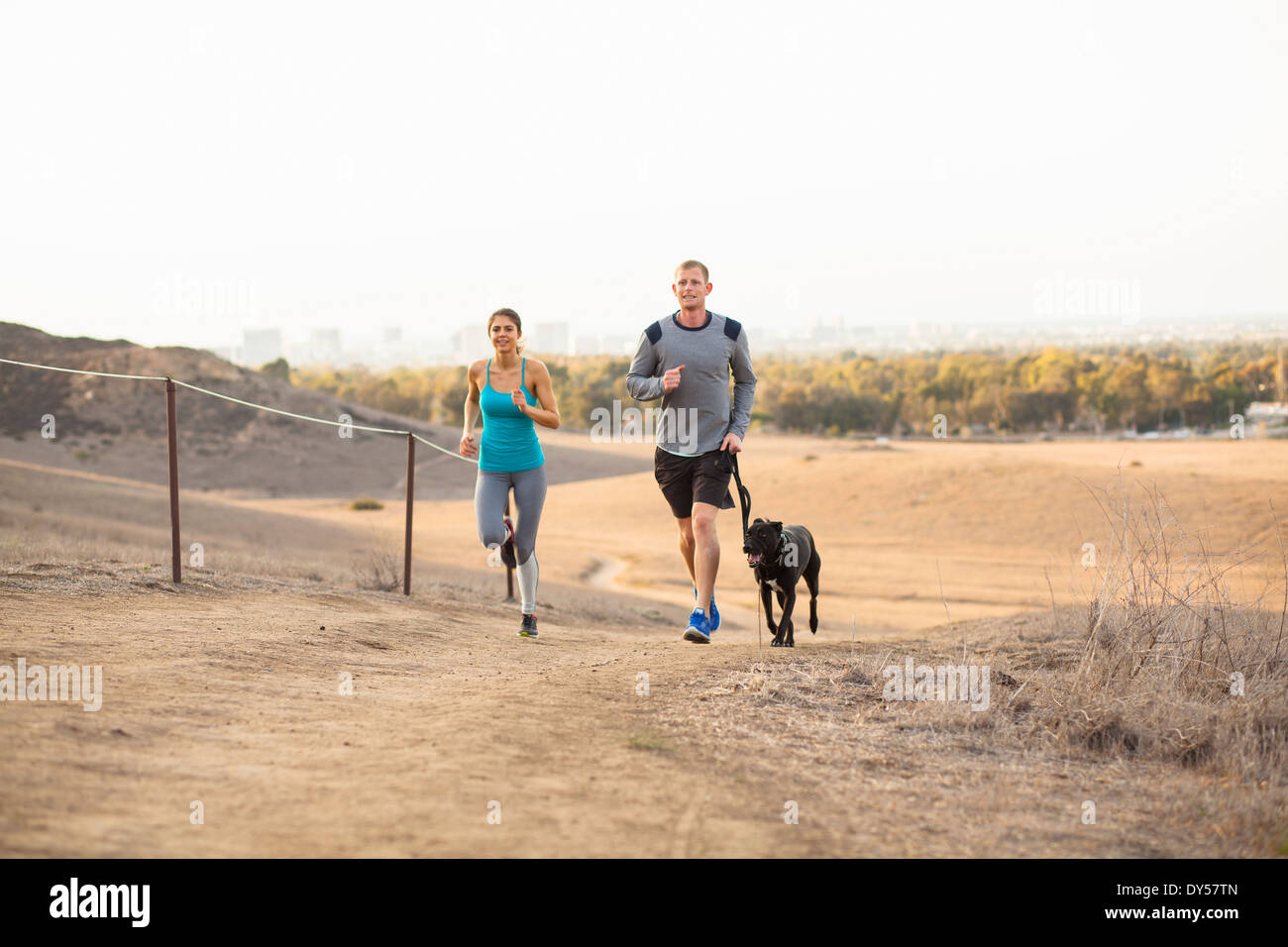 Couple running with dog Stock Photo - Alamy