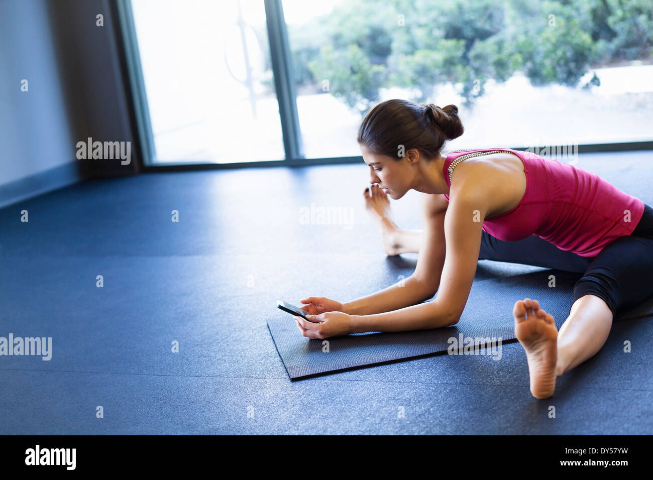 Young woman in yoga posture using cellular phone Stock Photo - Alamy