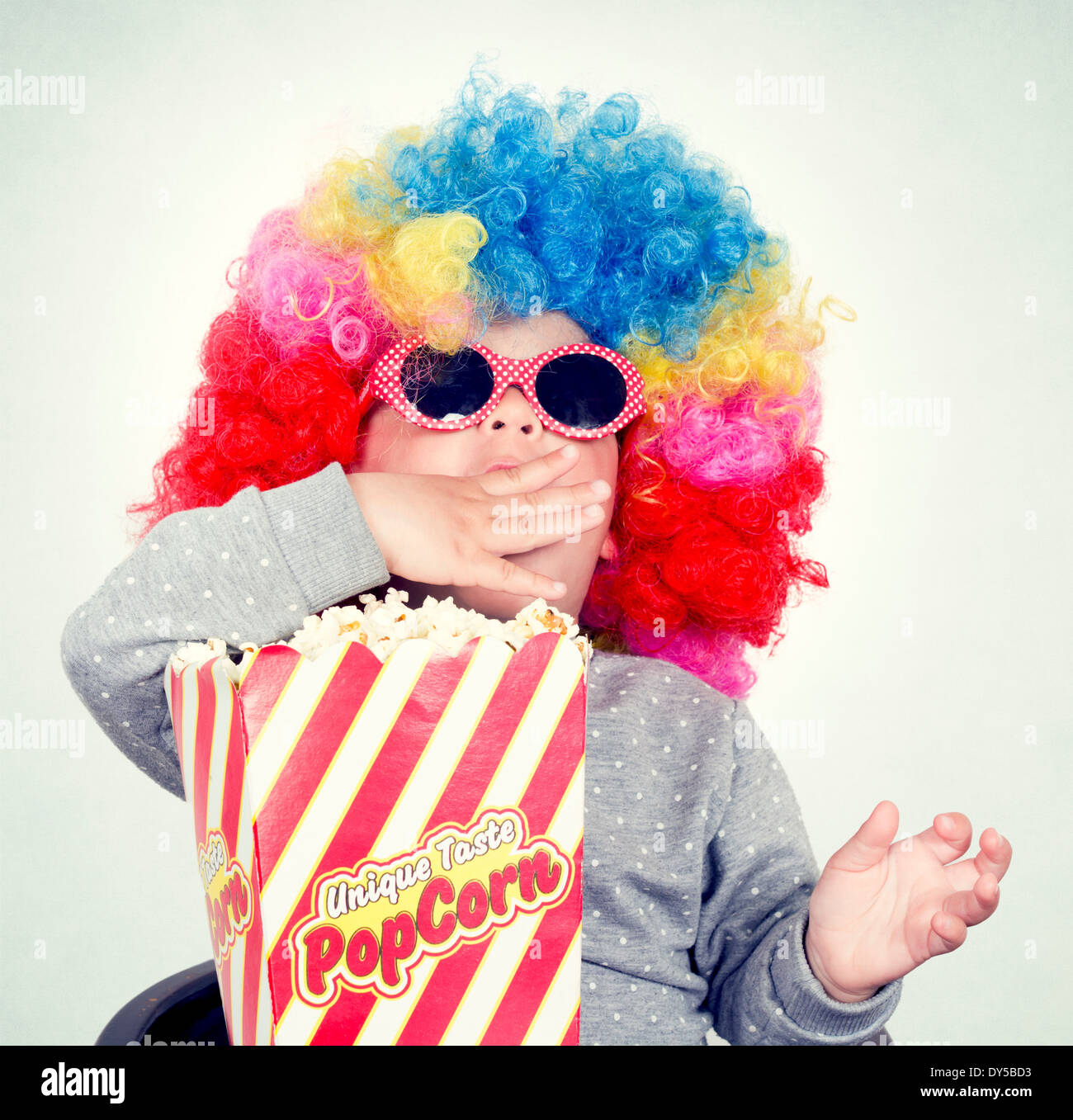 Child with clown wig and sunglasses eating pop corn Stock Photo - Alamy