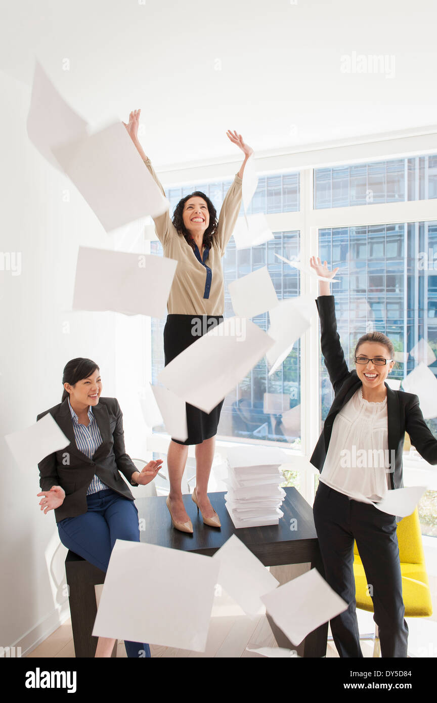 Three young businesswoman throwing papers mid air Stock Photo - Alamy