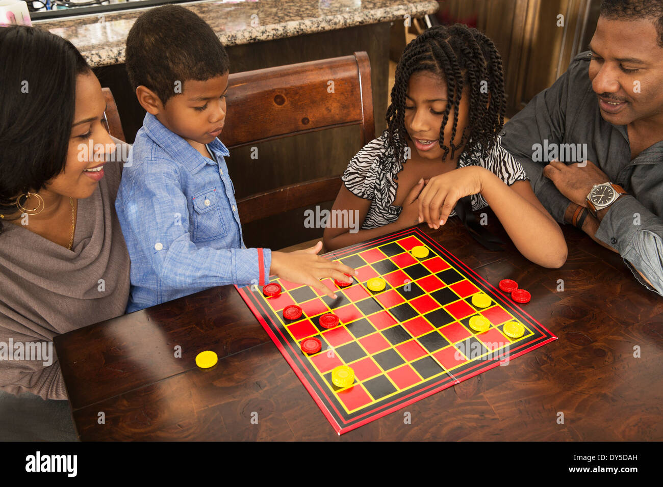 Mid adult couple and children playing draughts at dining table Stock ...